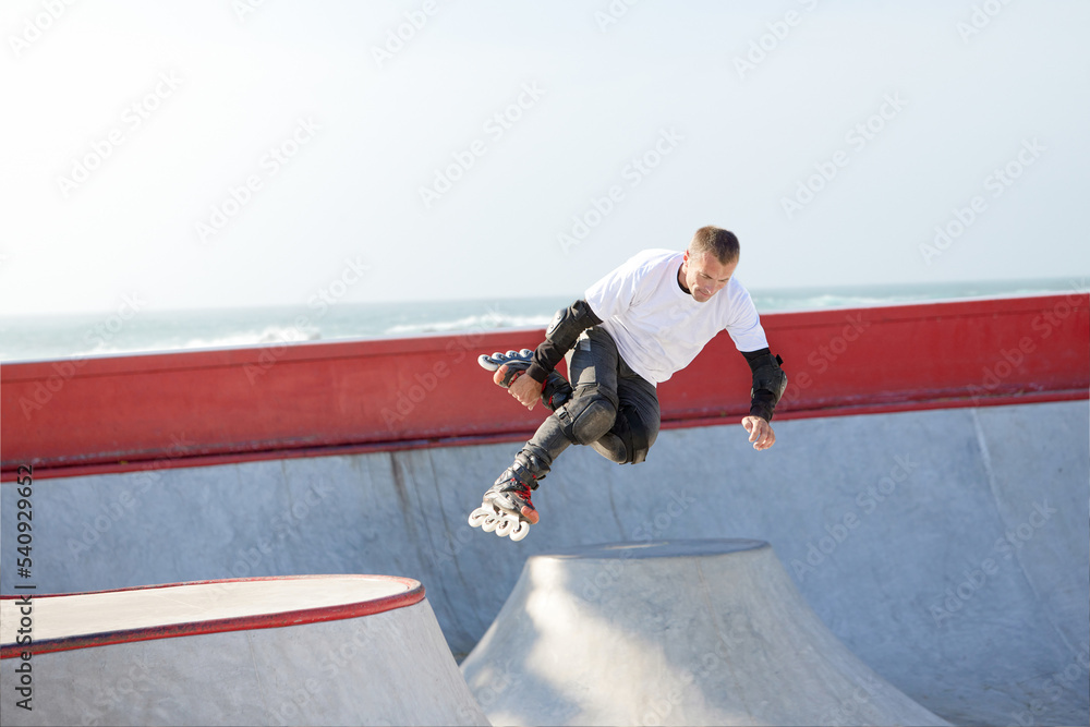 Energetic man on roller skates in motion at modern roller skate park ...
