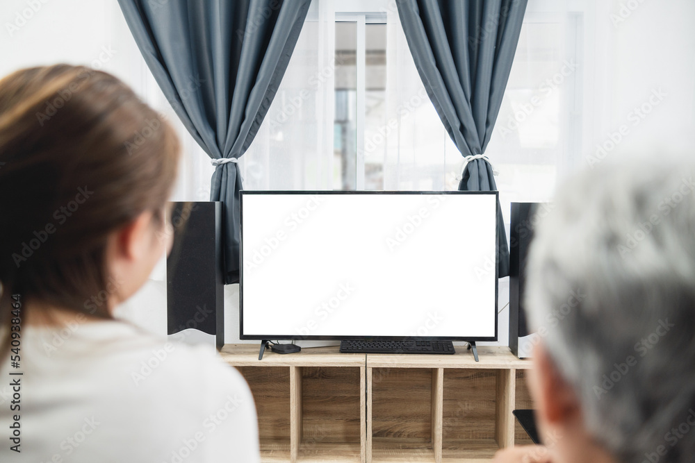 Asian senior woman and young woman sitting watching television in the ...