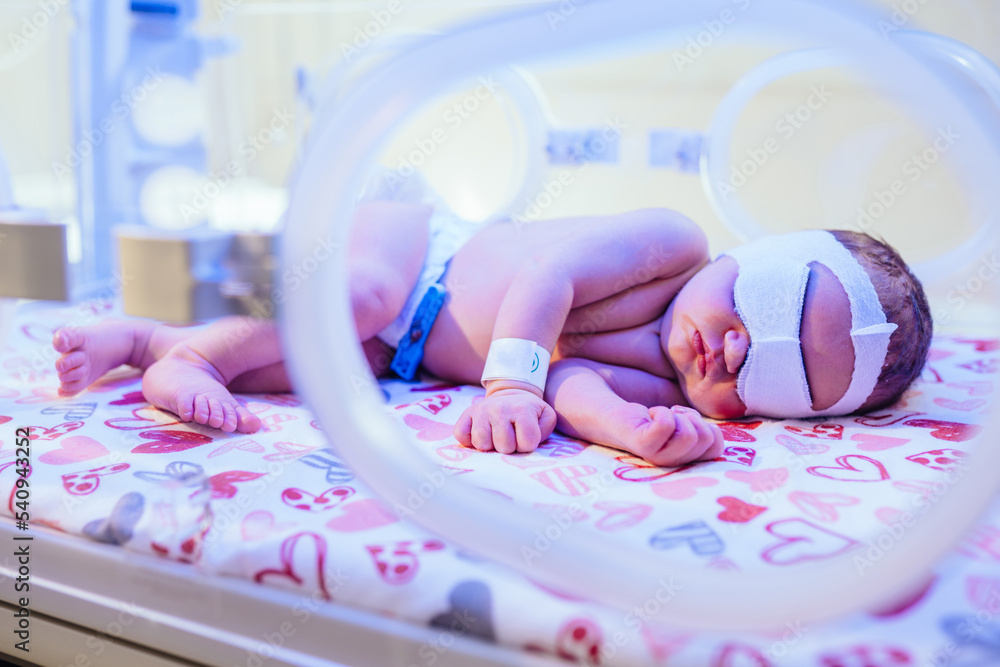 Portrait of new born baby girl under the ultraviolet lamp in hospital ...