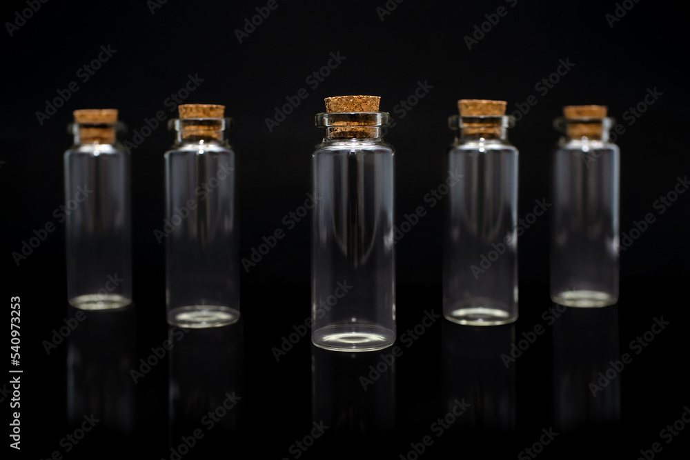 Five empty glass bottles on a black background with corks. Transparent ...