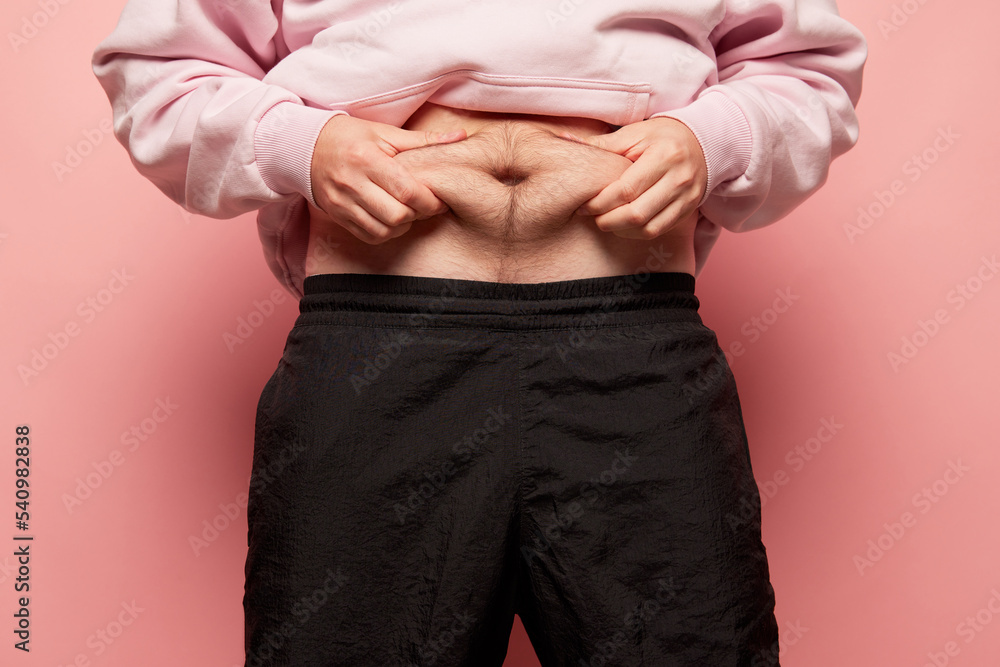 Closeup male hands stretching skin on his belly, man showing to camera ...