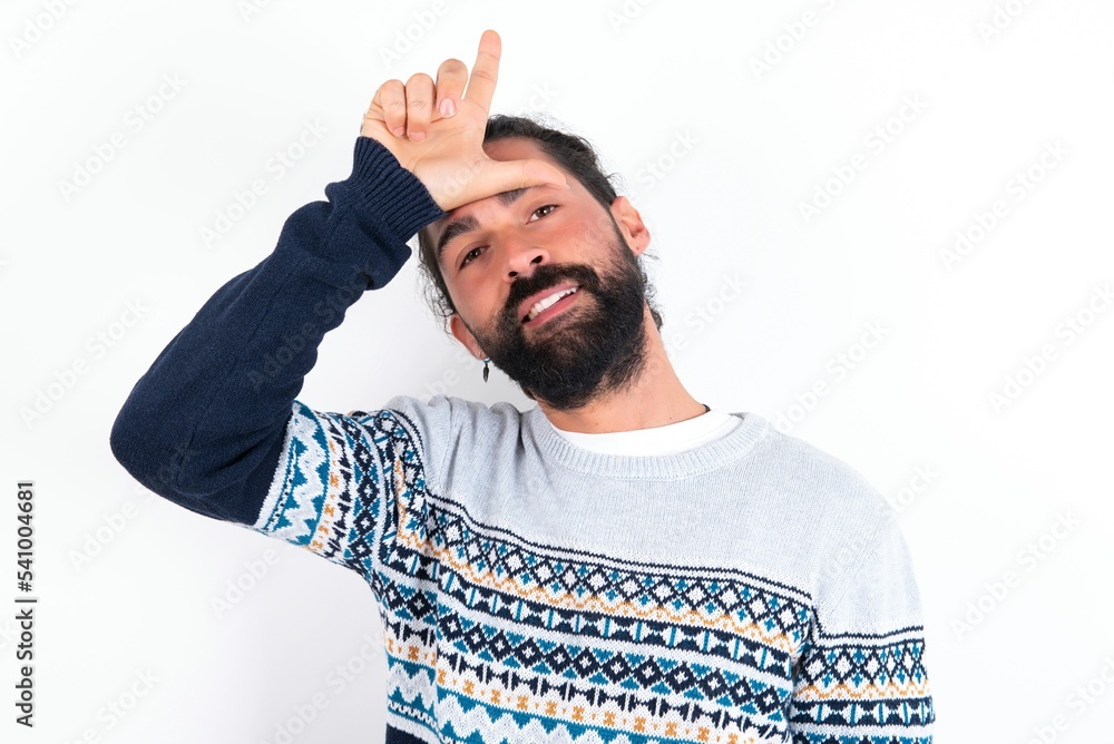 Funny young bearded hispanic man wearing knitted sweater over white ...