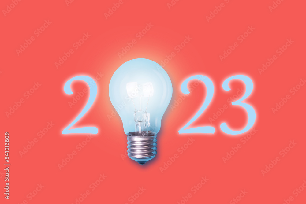 2023. Numbers and a glowing light bulb on an orange background. The ...