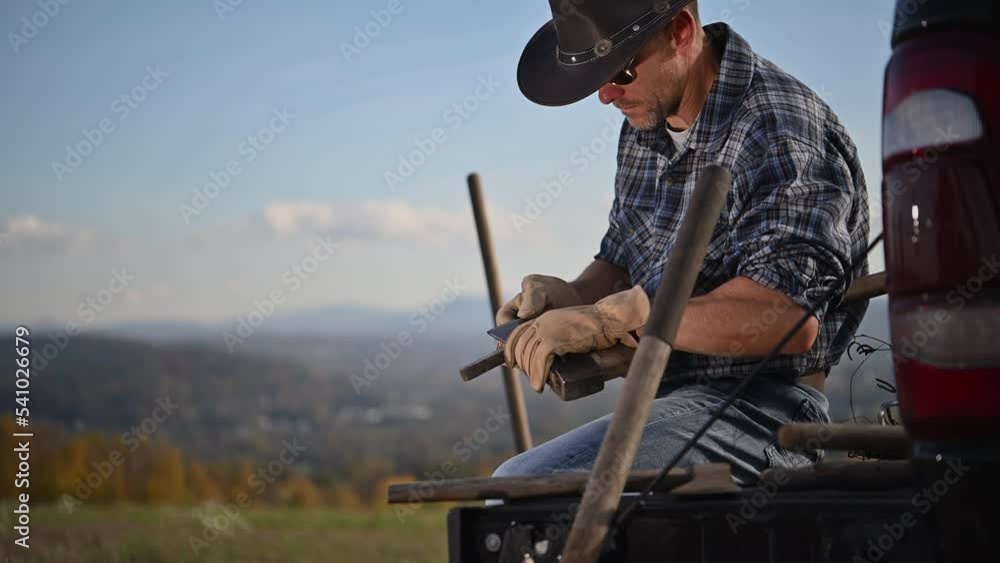 American Caucasian Cowboy in His 40s Sharpen an Axe While Seating on ...