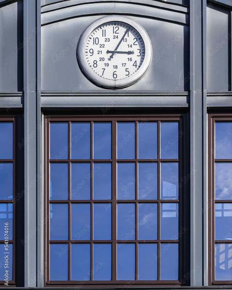 Street clock on the wall of the building above the windows, which ...