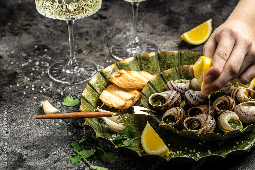 Delicious cooked sea escargo snails with herbs, butter, garlic on metal ...