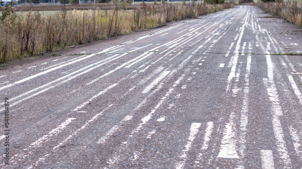 An abandoned road with white markings all over the asphalt surface. A ...