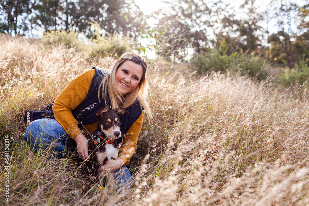 Happy country woman in her twenties with pet Australian Kelpie puppy ...