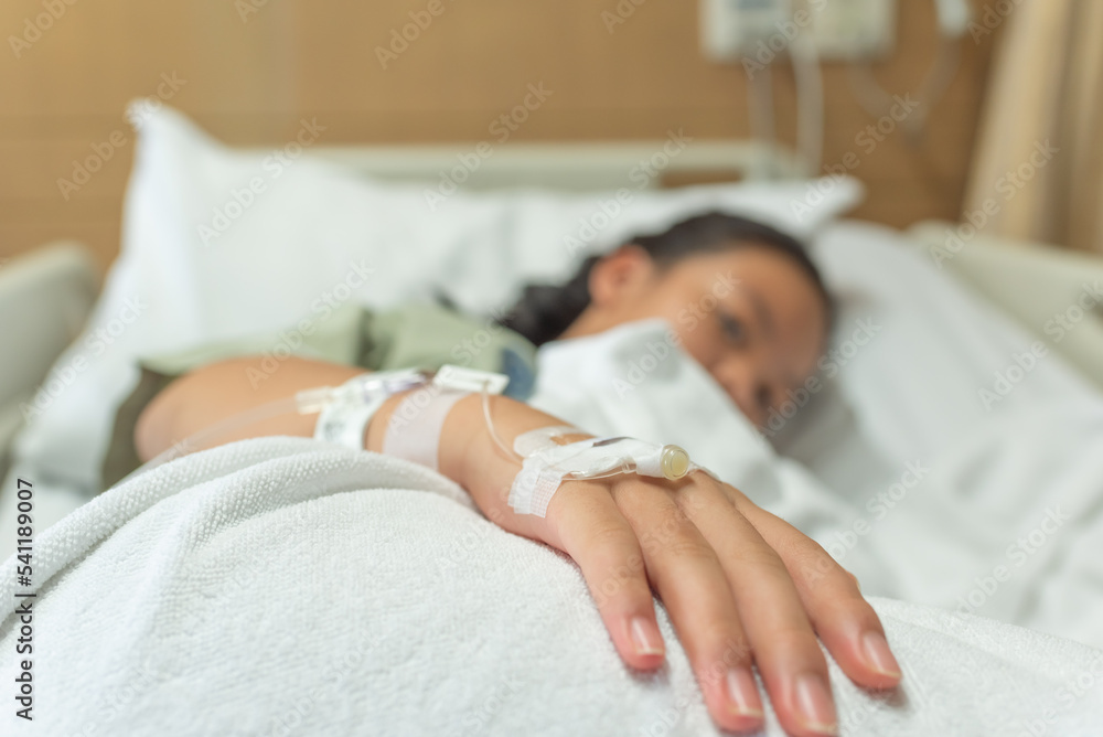 Young patient asian woman lying on bed in hospital with IV saline drip ...