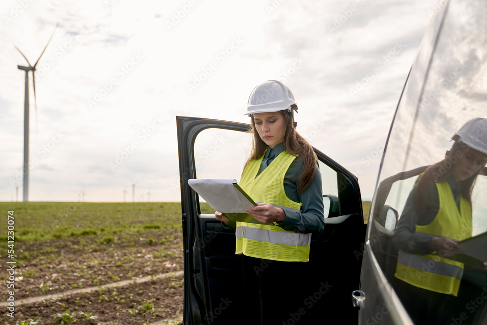 Female caucasian engineers standing on wind turbine field and checking ...
