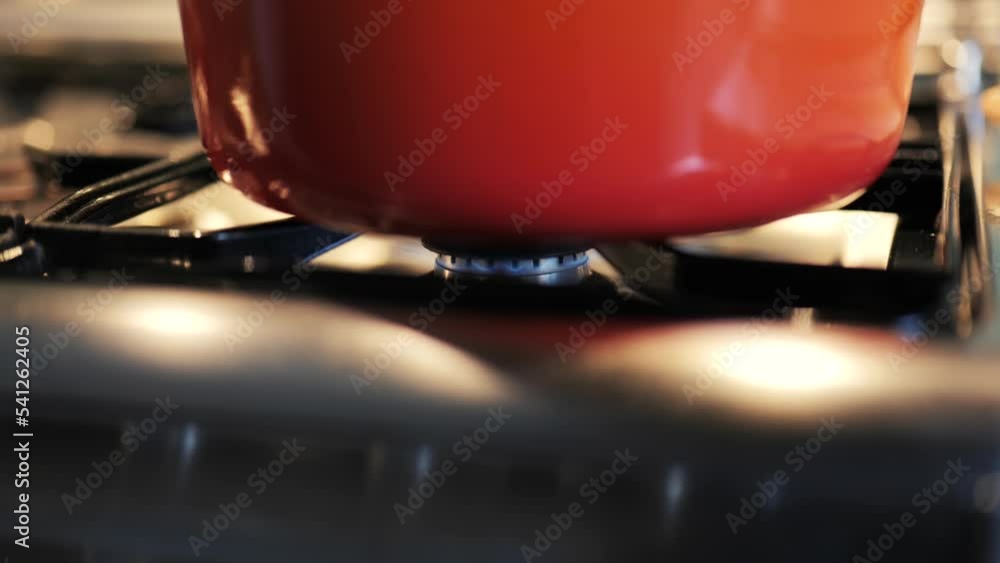 Focus on natural gas burner with blue flames under pot on cooking stove ...