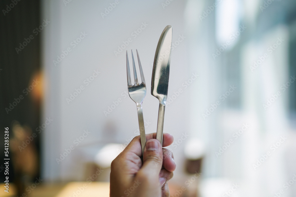 Hand holding fork and knife prepareing to start the breakfast. Blur ...