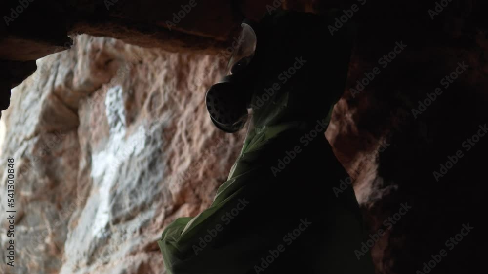 A man in a protective suit and a respirator gas mask stands at the exit ...