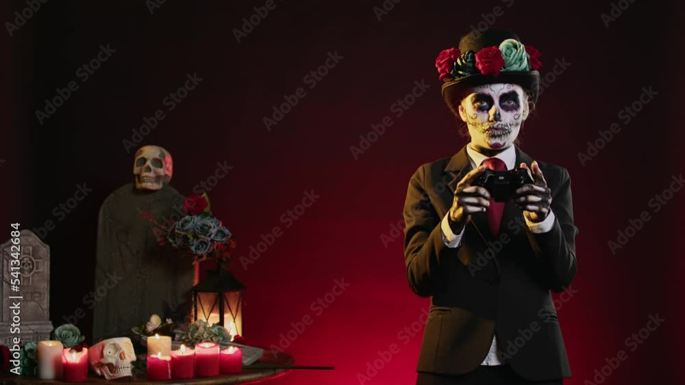 Model with santa muerte body art playing video games in studio, using ...