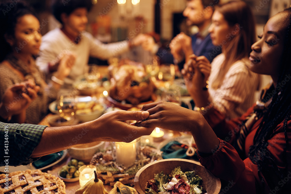 Close up of couple holding hands while praying with friends during ...