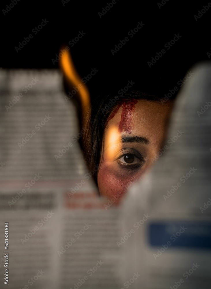 Vertical shot of a female eye with a bloody forehead seen through ...