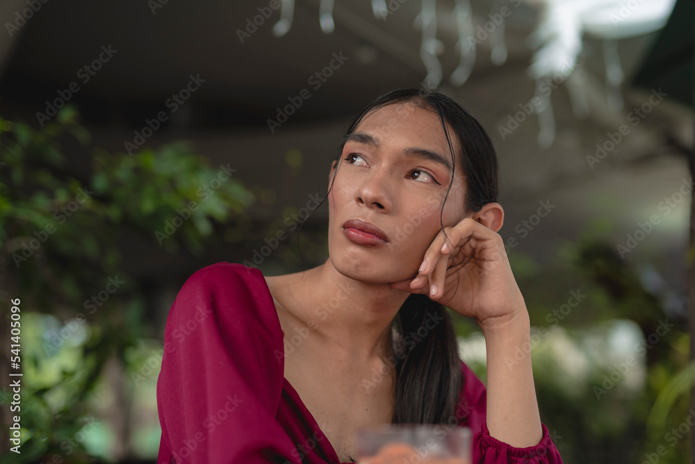 A sad looking trans woman sitting outside rests her head on her ...