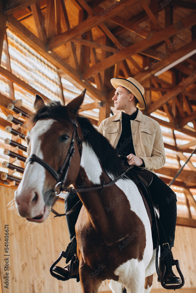 Handsome cowboy man riding a horse on a ranch. Stock Photo | Adobe Stock
