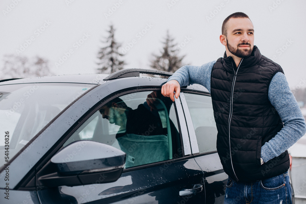 Handsome man in warm jacket standing by car covered with snow Stock ...