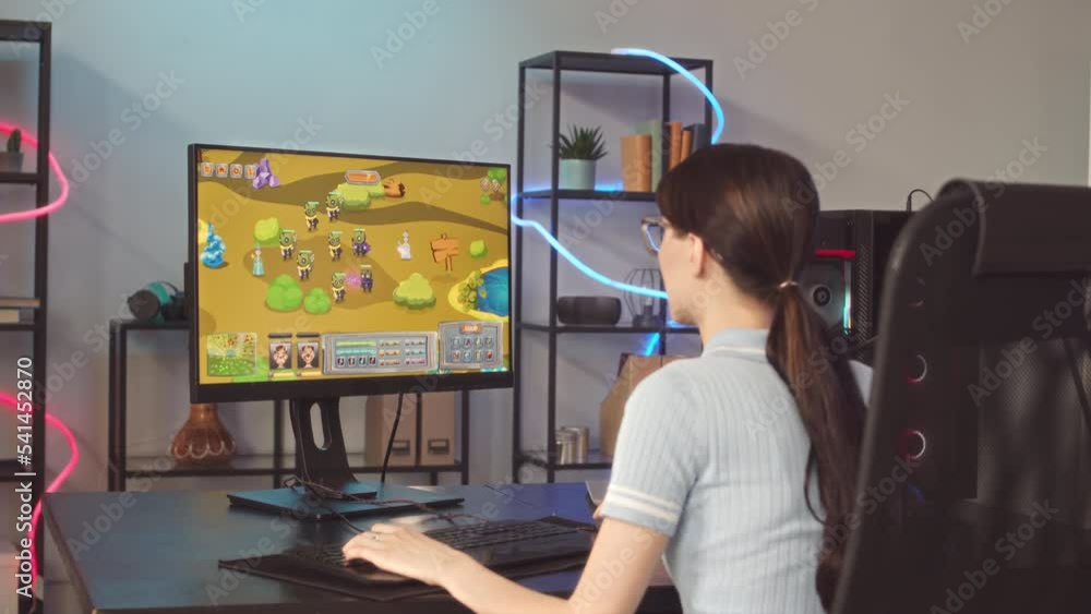 Rear view shot of girl in her early 20s playing rpg game on pc using ...