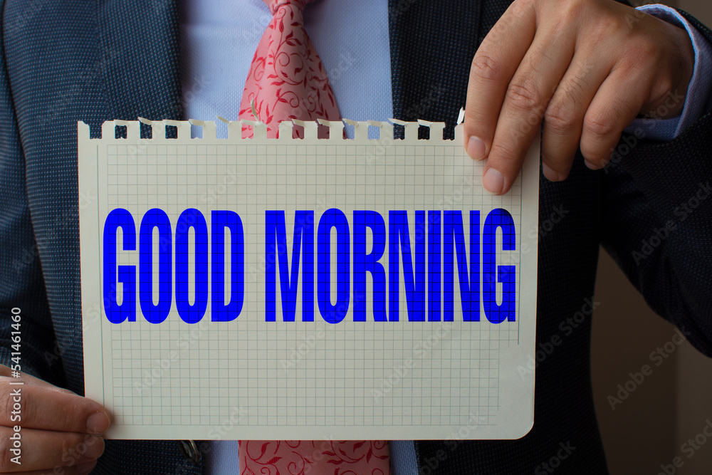 The paper in the hand of the man in the suit reads ''good morning ...