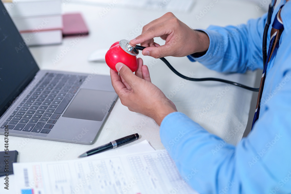 Male medicine doctor holding red heart and stethoscope head in front of ...