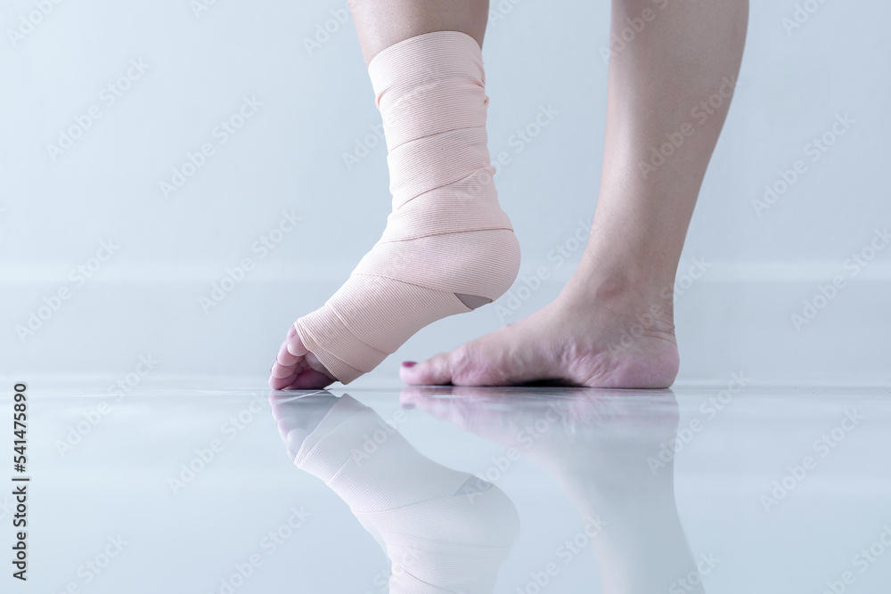 Woman holding her leg with sprained ankle and elastic bandage isolated ...
