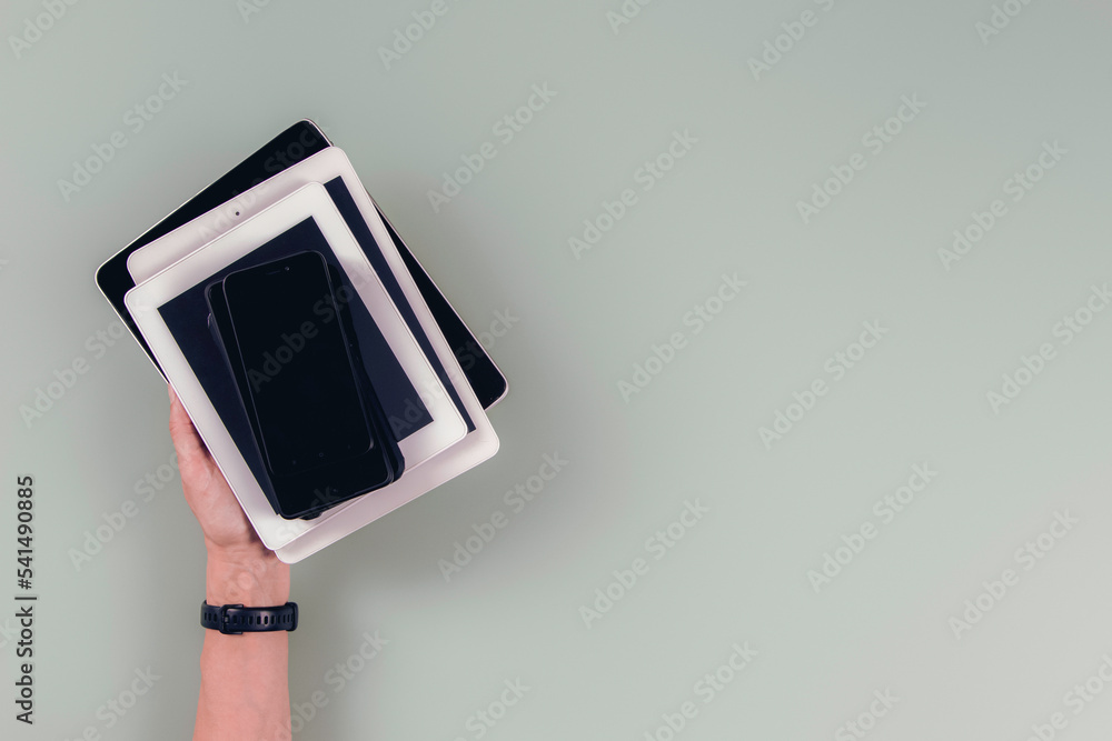 Woman hand holding pile of digital tablet computers and smartphones ...