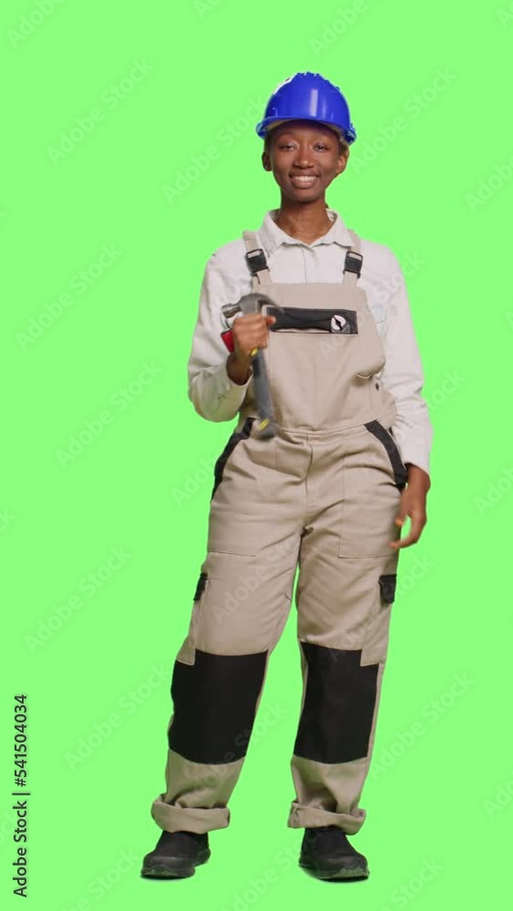 Vertical video: African american handywoman holding hammer to hit walls ...