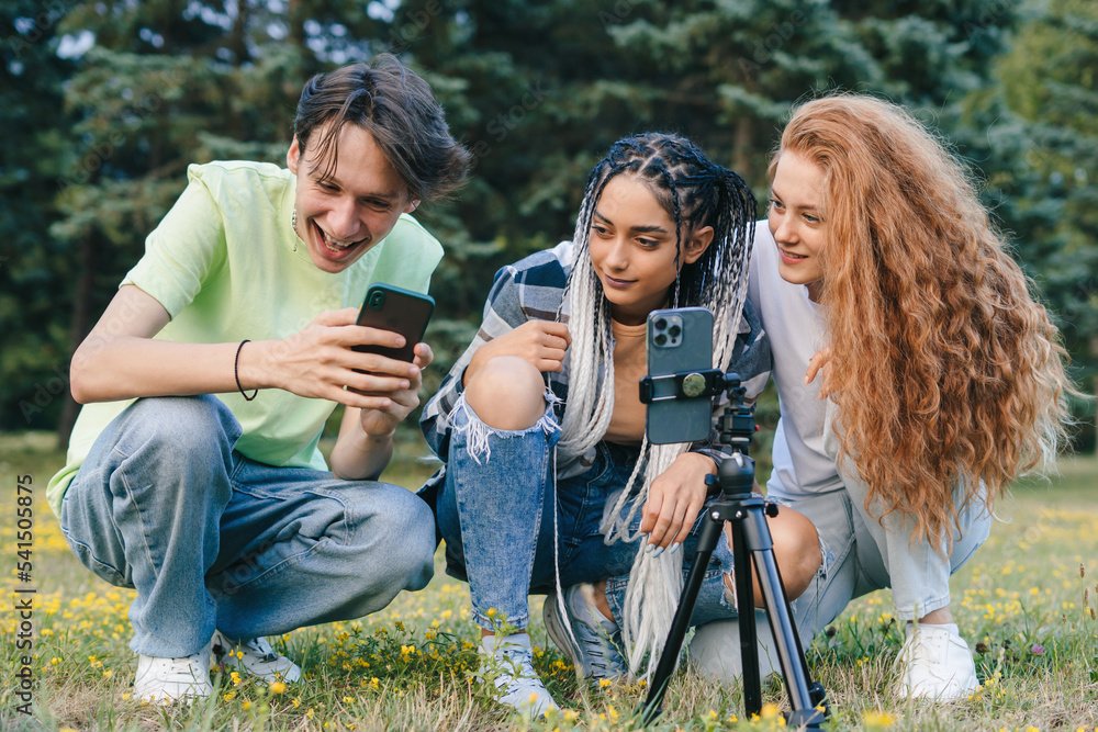 Generation Z friends standing in the park watching viral videos on the ...