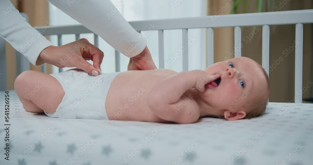 Side view portrait of small baby when his mother changing diaper on the ...