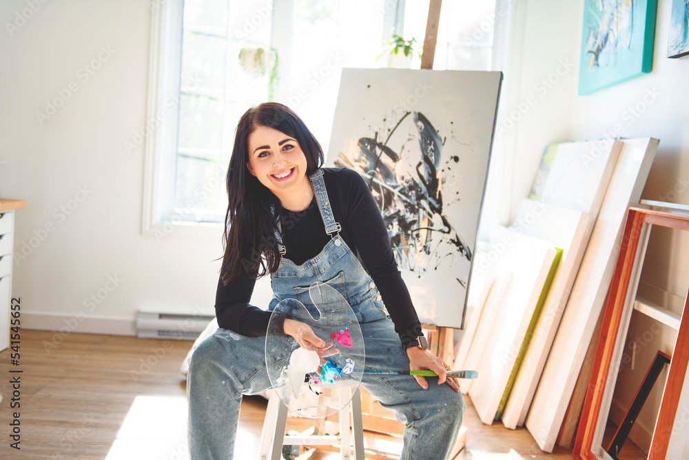 Portrait of a woman artist working on several art projects on her ...