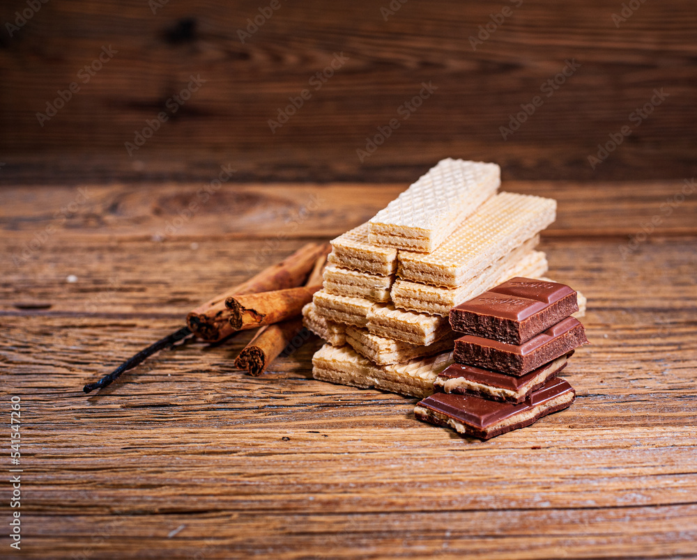 Chocolate, wafers, cinnamon sticks and vanilla stick on a wooden ...