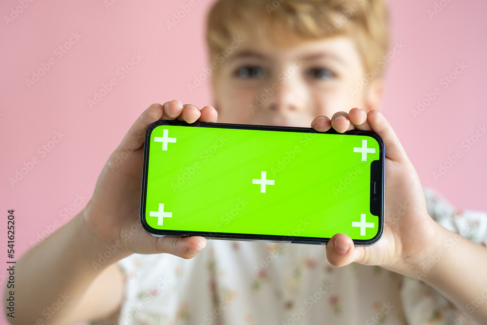 Little cute child girl show smartphone blank horizontal green screen ...