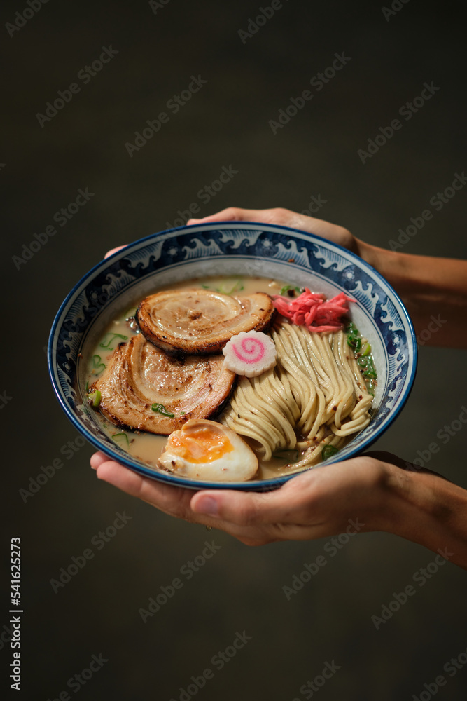 From above anonymous woman carrying bowl with delicious ramen with pork ...
