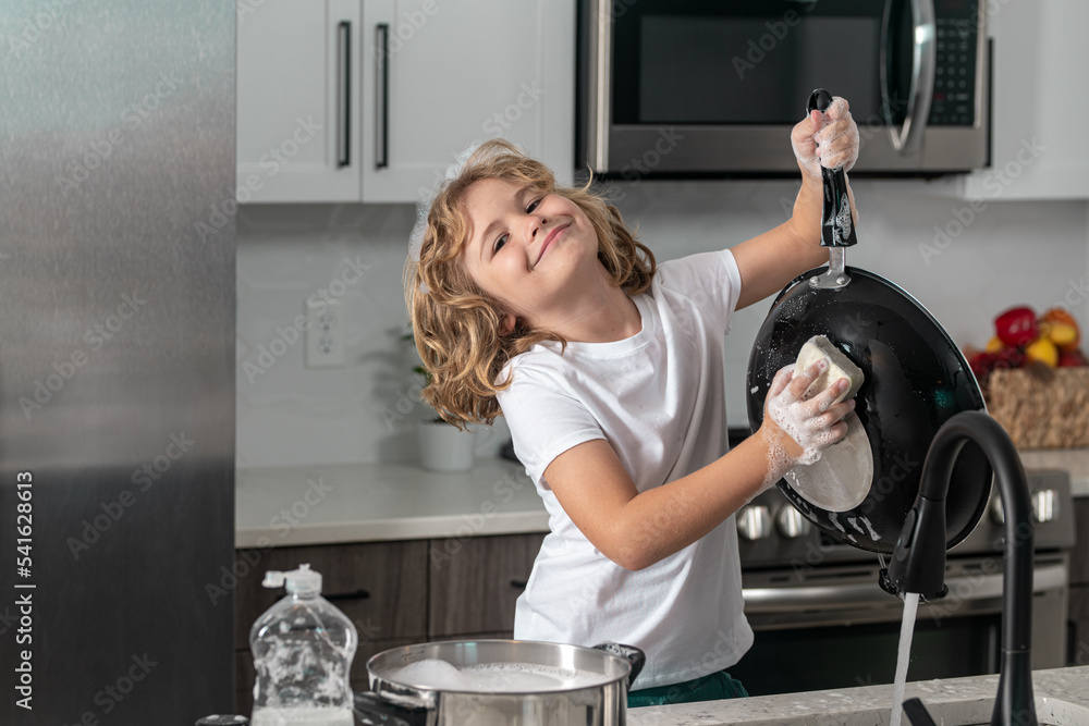 Funny child help in washing dishes at kitchen. Dishwashing liquid ...