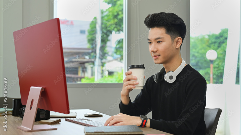 Professional creative man drinking coffee and working with computer in ...