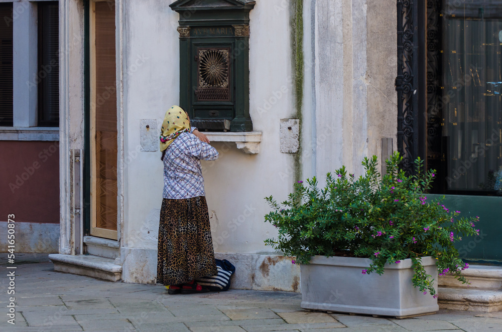 Una zingara prega davanti a un tabernacolo dedicato alla madonna in una ...