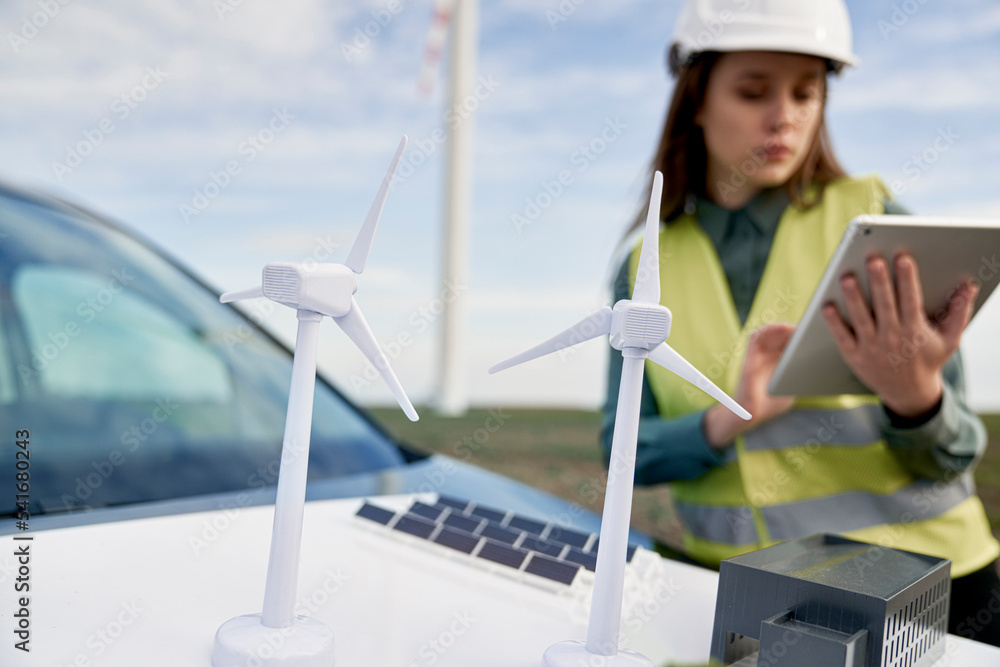 Female caucasian engineer browsing digital laptop and wind turbine ...