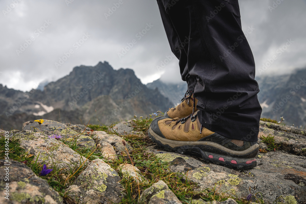 tourist's feet on the rock of the mountain top, in trekking shoes for a ...