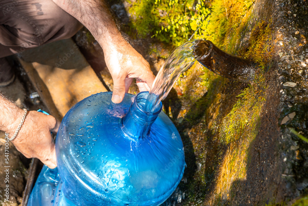 The process of pouring pure spring water from an artesian well into a ...