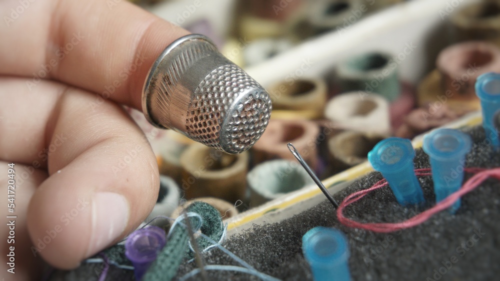 Metal thimble on the finger for sewing Stock Photo | Adobe Stock