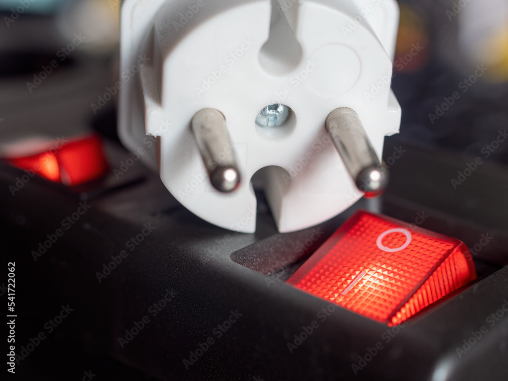 Illuminated power switch on a socket with a European Schuko plug as a ...