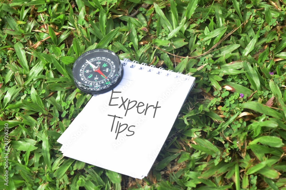 Expert Tips wording on a paper with a compass over a green grass ...