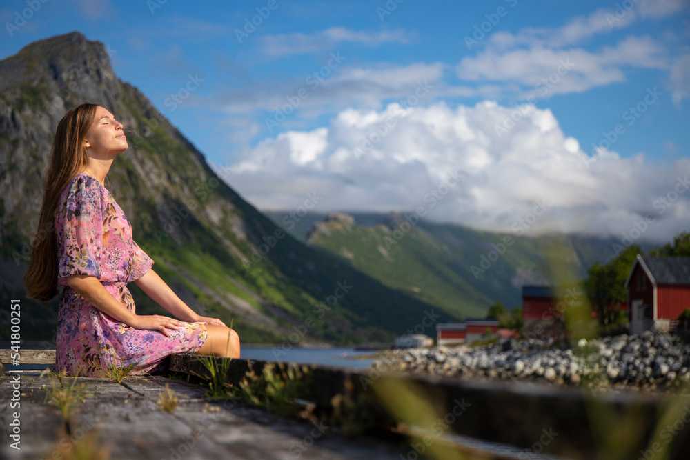 long-haired girl in purple dress sits on rocks with a red house and ...