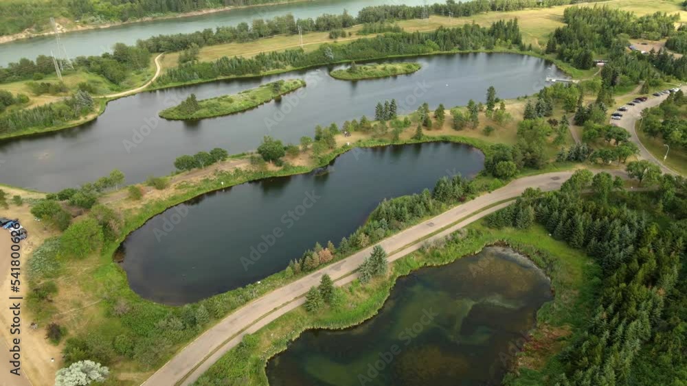 Zoom out Drone shot of a park pond as birds fly by. There are three ...