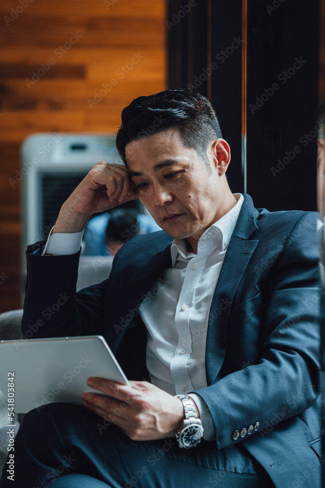 Handsome Asian man in elegant blue suit analyzing business report on ...