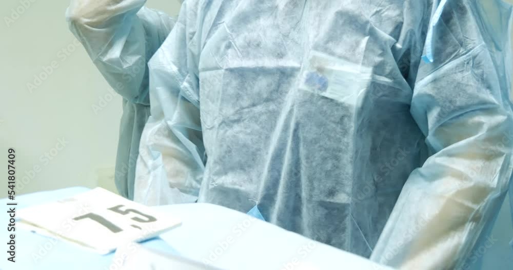 The surgeon is getting ready for the operation. The assistant helps the ...