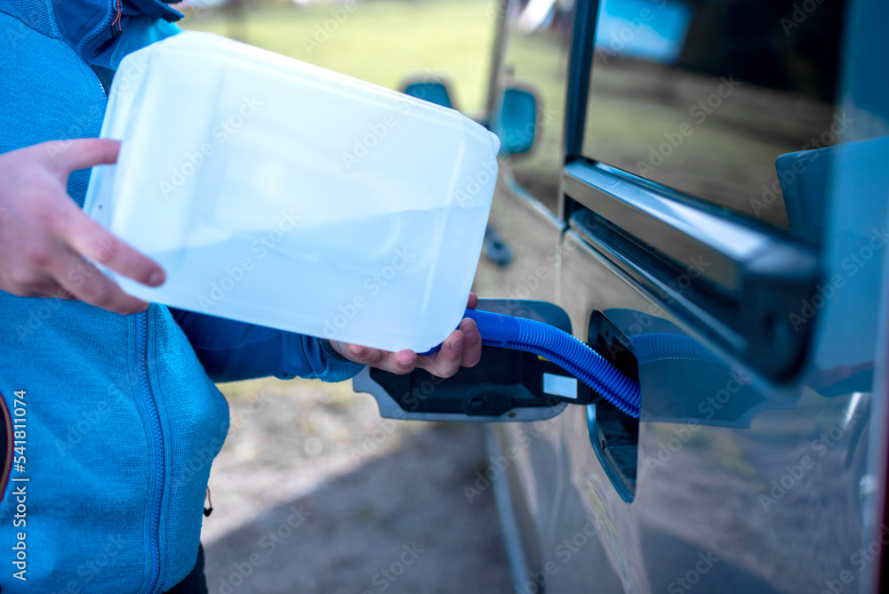 Pouring adblue to the car. Male driver adding Diesel exhaust fluid to ...
