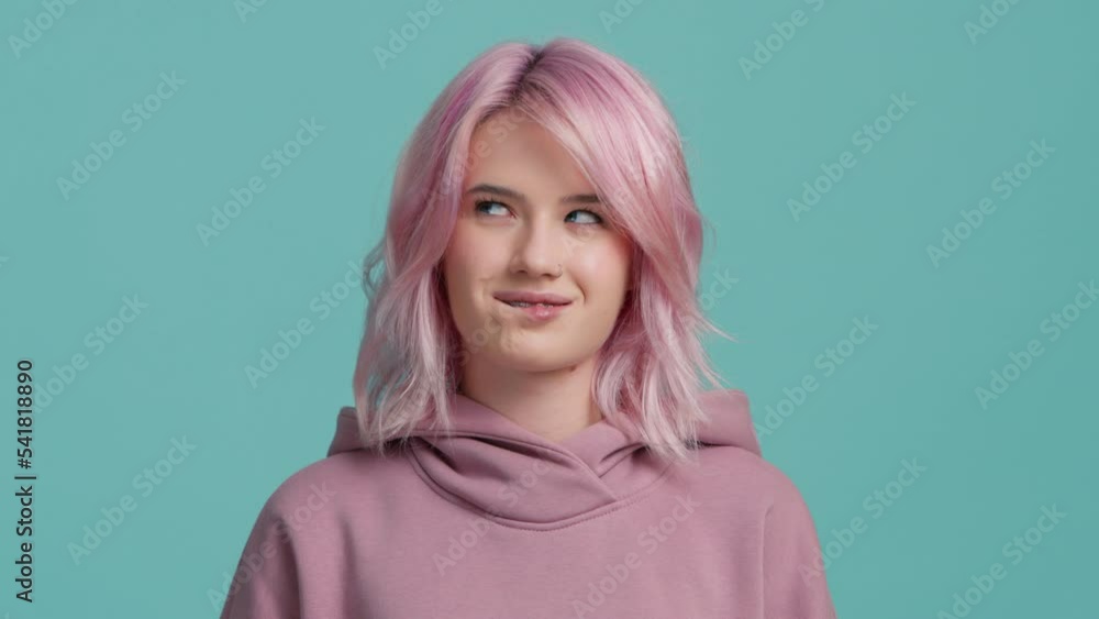 Cunning young woman with pink color hairstyle in hoodie thinking ...